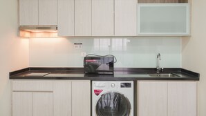 Uma cozinha compacta com máquina de lavar embutida, micro-ondas e pia.