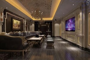 Um hall de entrada luxuoso com um piano de cauda, assentos confortáveis, uma grande tela de televisão e um lustre.