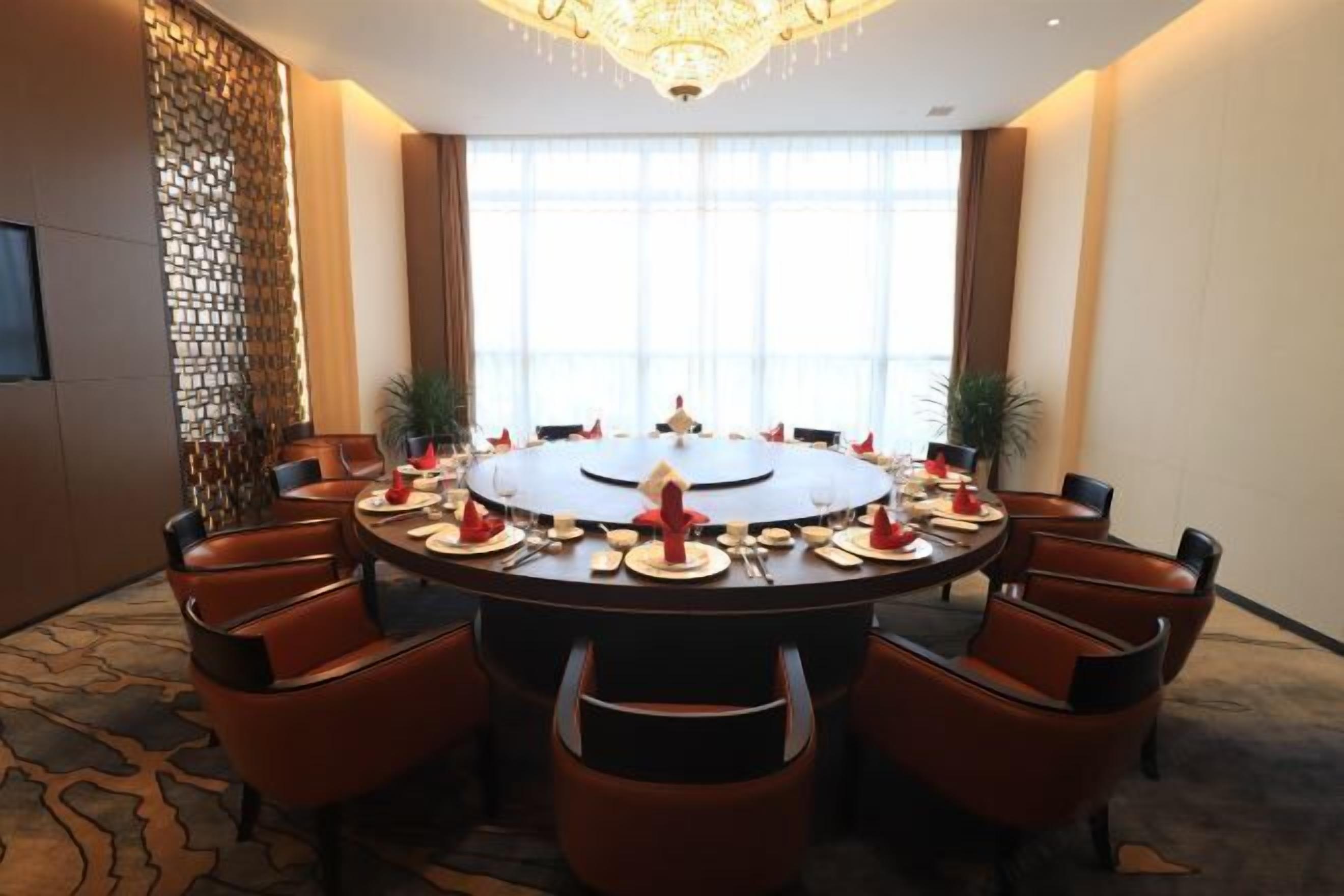 Uma sala de conferências com uma mesa redonda, oito cadeiras e um lustre.