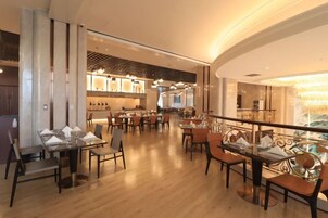 Um restaurante amplo com pé direito alto, iluminação moderna e diversas opções de assentos.