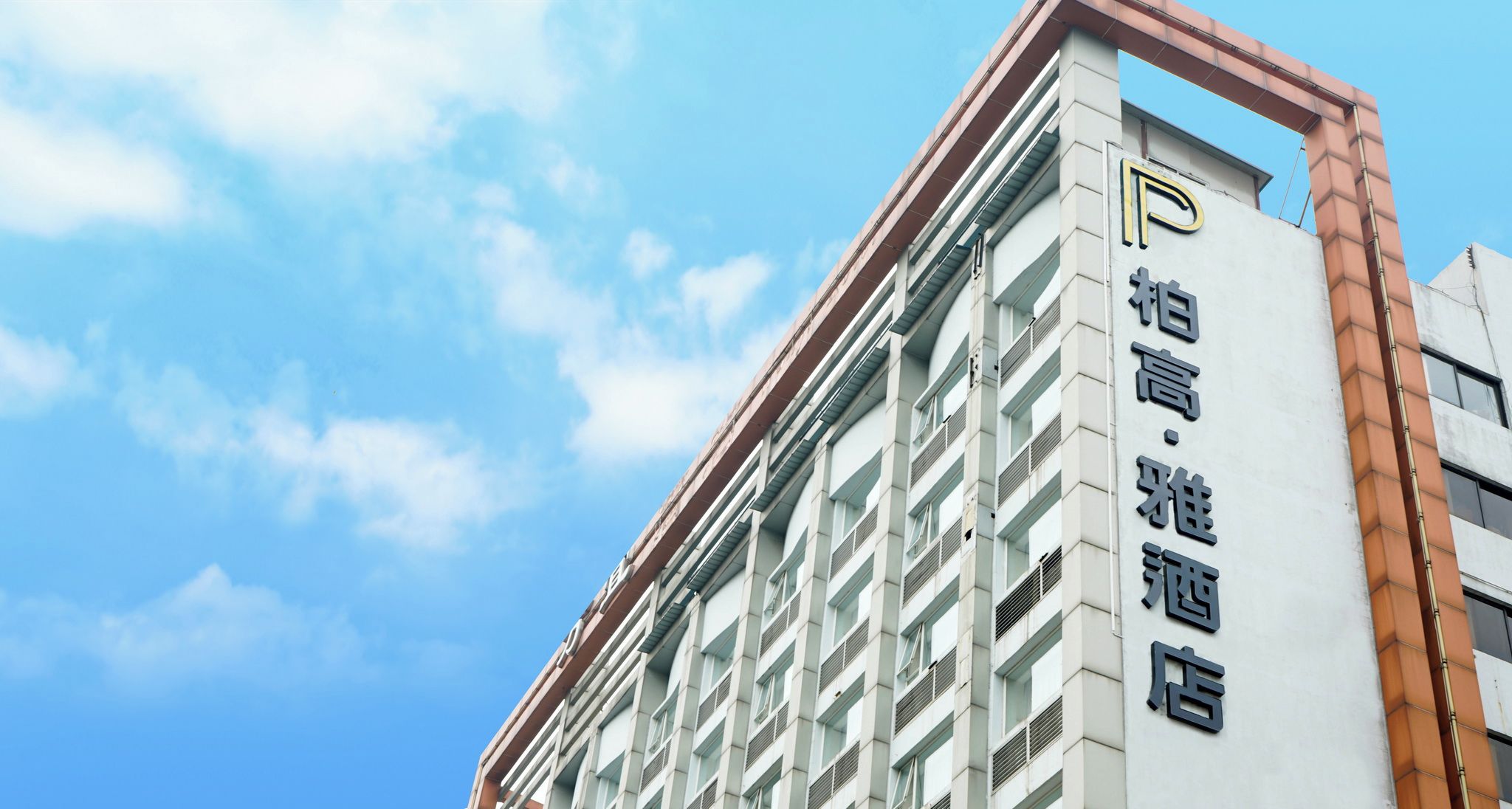 Edifício de hotel com vários andares e design arquitetônico moderno, com entrada destacada e estrutura metálica geométrica.