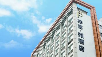 Edifício de hotel com vários andares e design arquitetônico moderno, com entrada destacada e estrutura metálica geométrica.