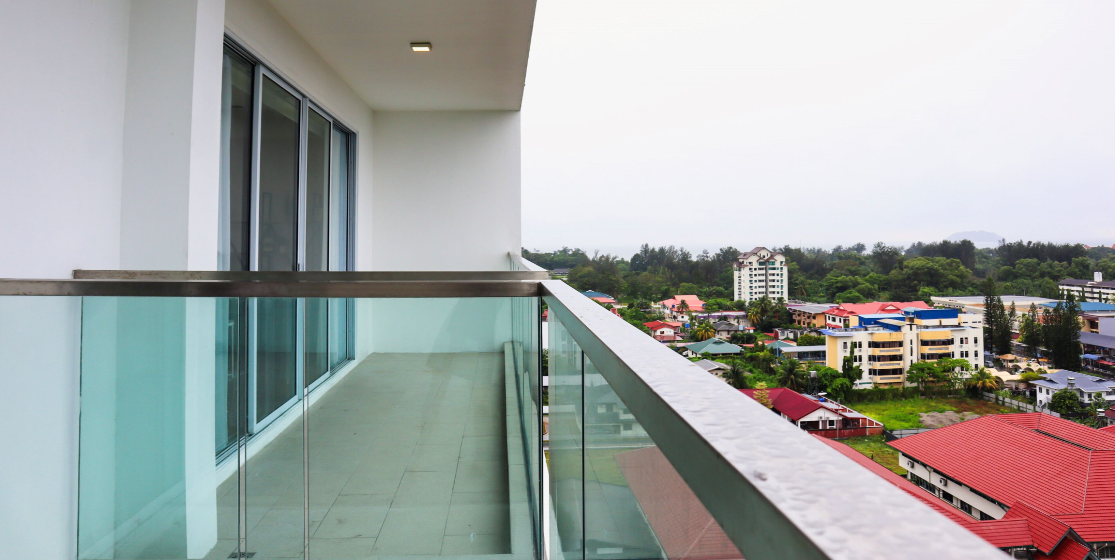Varanda com guarda-corpo de vidro com vista para um horizonte urbano com vários edifícios.