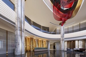 Um hall amplo com teto alto, colunas de mármore e área de estar central.