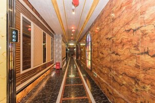 Corredor com piso de mármore, painéis de madeira e placa indicando o quarto 666.