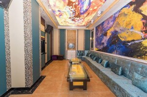 Um hall de hotel com uma mesa de centro, área de estar e uma grande pintura abstrata na parede.