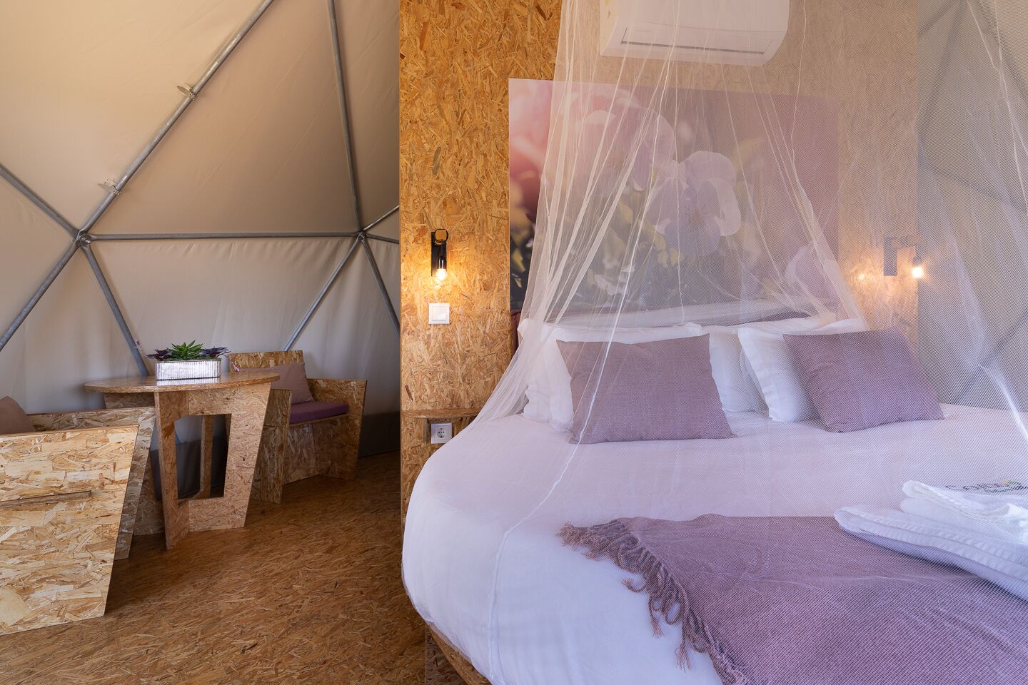 Um quarto em estilo de tenda aconchegante, com cama, uma mesinha e um espaço para sentar.