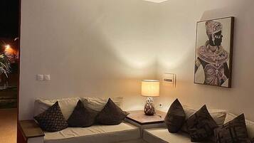 Uma sala de estar moderna com um sofá, uma mesinha de apoio, um abajur e um tapete decorativo.