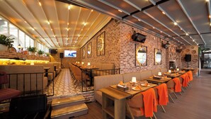 Um restaurante com paredes de tijolo, mesas de madeira e toalhas de mesa laranja.