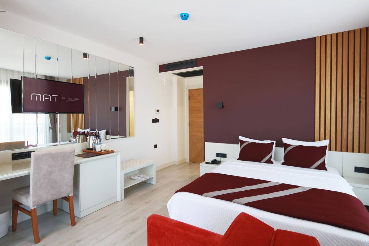 Quarto de hotel moderno com uma cama grande, uma escrivaninha e uma televisão.