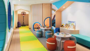 Uma área de recreação infantil com assentos coloridos, uma cesta de basquete e brinquedos educativos.