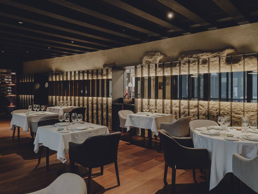 Restaurante com várias mesas, piso de madeira e design de interiores moderno.