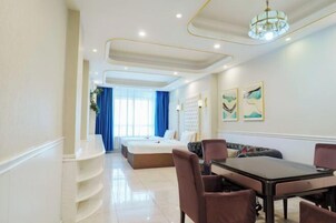 Quarto de hotel com cama, mesa de jantar com cadeiras, lustre e obras de arte na parede.