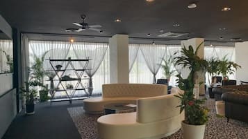 Uma sala de estar moderna com um sofá curvo, uma mesa de centro e uma grande planta em vaso.