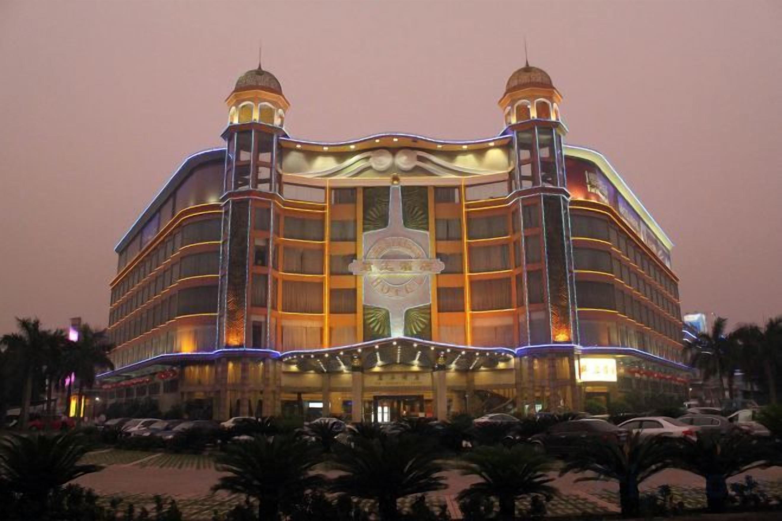 Um hotel com vários andares, um átrio central, várias varandas e uma entrada espaçosa.