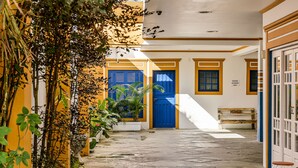 Um corredor com piso de azulejos, portas azuis e detalhes em amarelo.