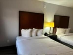 Quarto de hotel com uma cama grande, mesa de cabeceira com luminária e cabeceira.