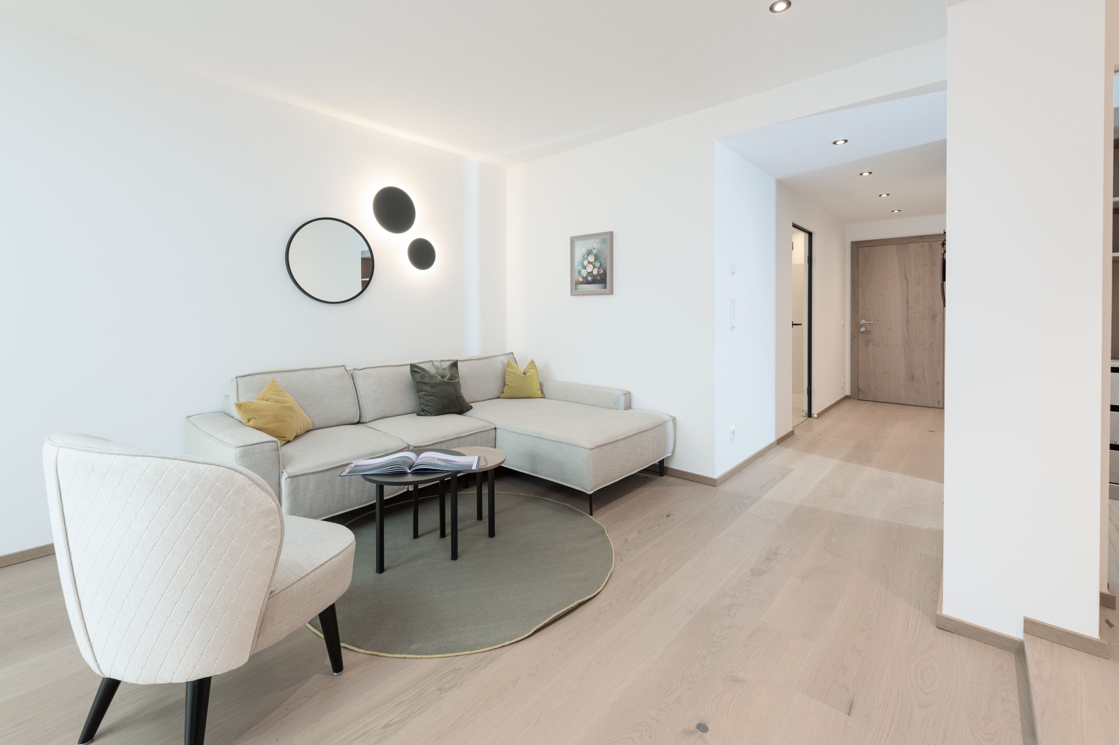 Uma sala de estar moderna com sofá, poltronas, mesa de centro e um tapete pequeno.