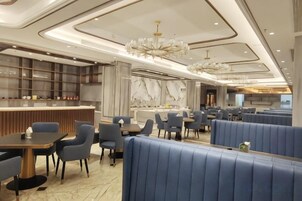Um restaurante moderno com área de bar, mesas e um candelabro.