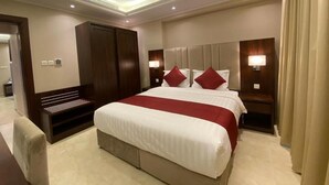 Quarto de hotel com uma cama grande, guarda-roupa, abajures e iluminação embutida no teto.