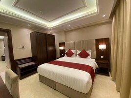 Quarto de hotel com uma cama grande, guarda-roupa, abajures e iluminação embutida no teto.