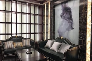 Quarto com um sofá de couro escuro, uma mesa de centro e uma grande pintura abstrata na parede.