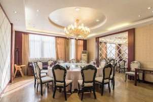 Uma sala de jantar com mesa redonda, cadeiras e um lustre.