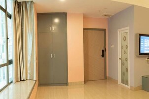 Quarto de hotel com um guarda-roupa espaçoso, porta com painéis de vidro jateado e televisão fixada na parede.
