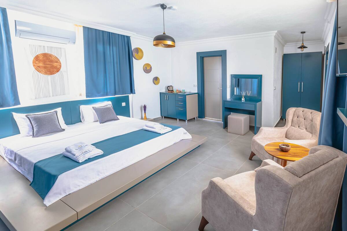 Quarto de hotel moderno com uma cama grande, uma escrivaninha, uma cadeira e um guarda-roupa.