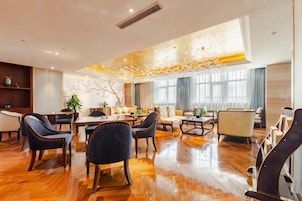Um amplo hall de hotel com piso de madeira, área de refeições central e disposição de assentos.