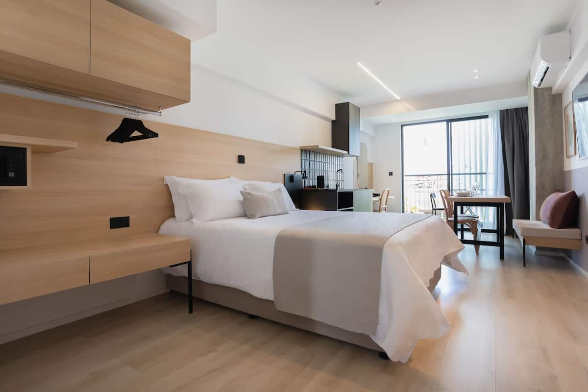 Quarto de hotel moderno com uma cama grande, uma escrivaninha e uma varanda com vista.