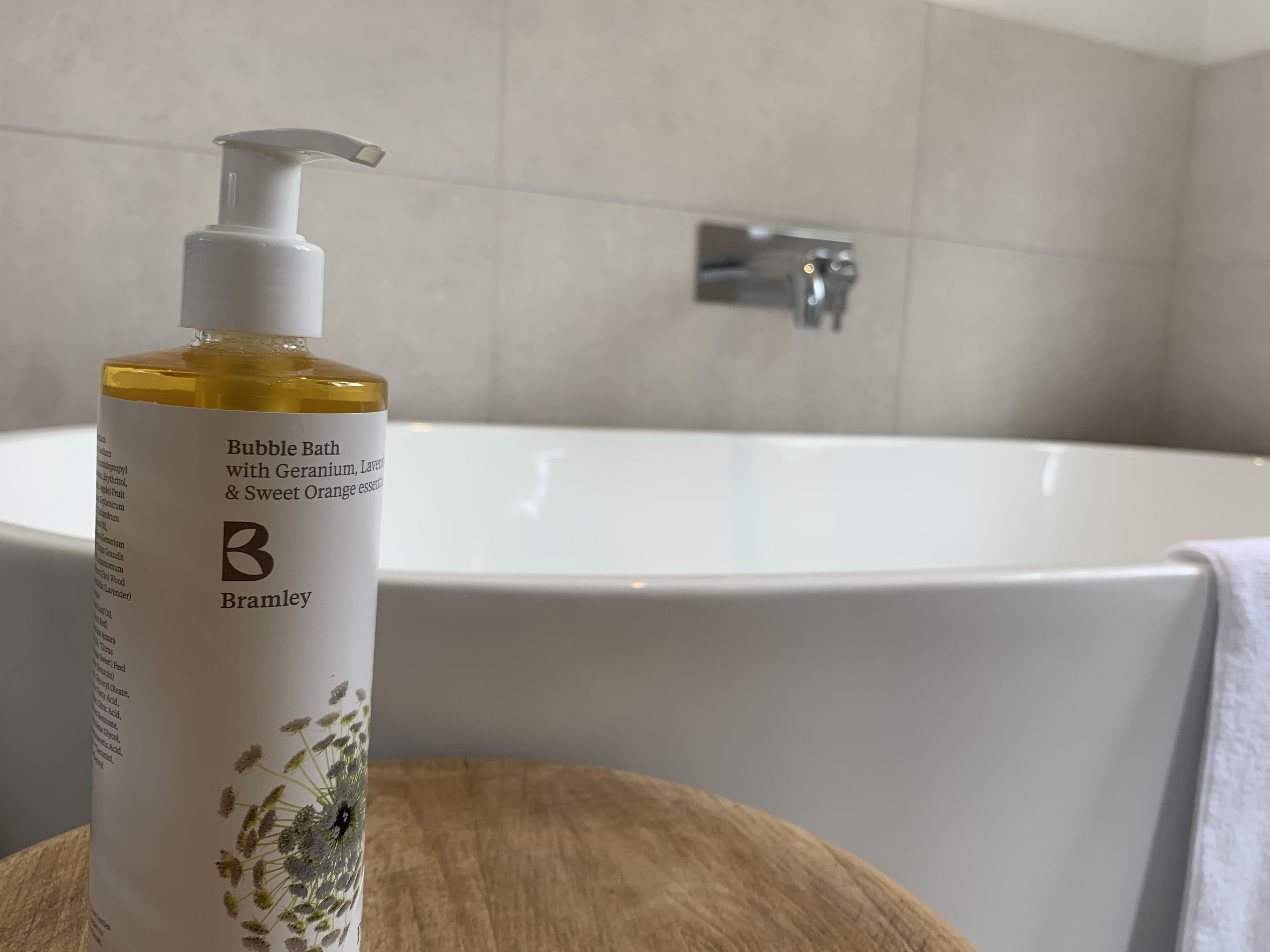 Um banheiro com uma banheira, um frasco de sais de banho e uma superfície de madeira.