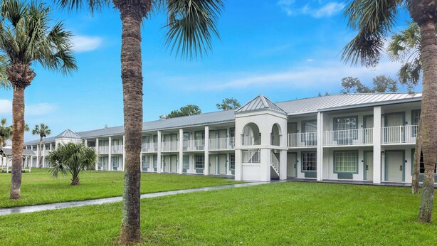 Um motel com um pátio central, várias varandas e palmeiras.