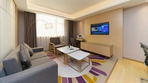 Quarto de hotel moderno com sofá, mesa pequena, televisão e escrivaninha.