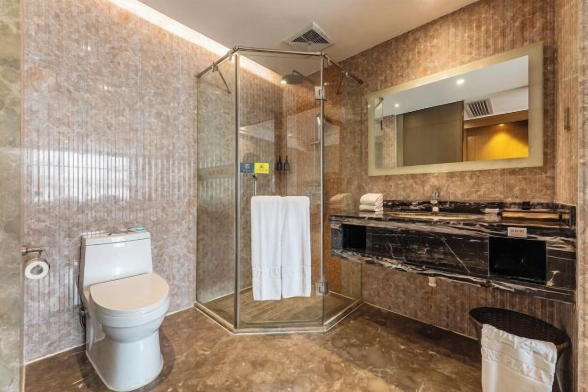 Uma casa de banho moderna com cabine de duche em vidro, sanita e lavatório com espelho.