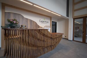 Uma receção com design em madeira e um letreiro que diz "Cape Kris Boutique Hotel & Spa".