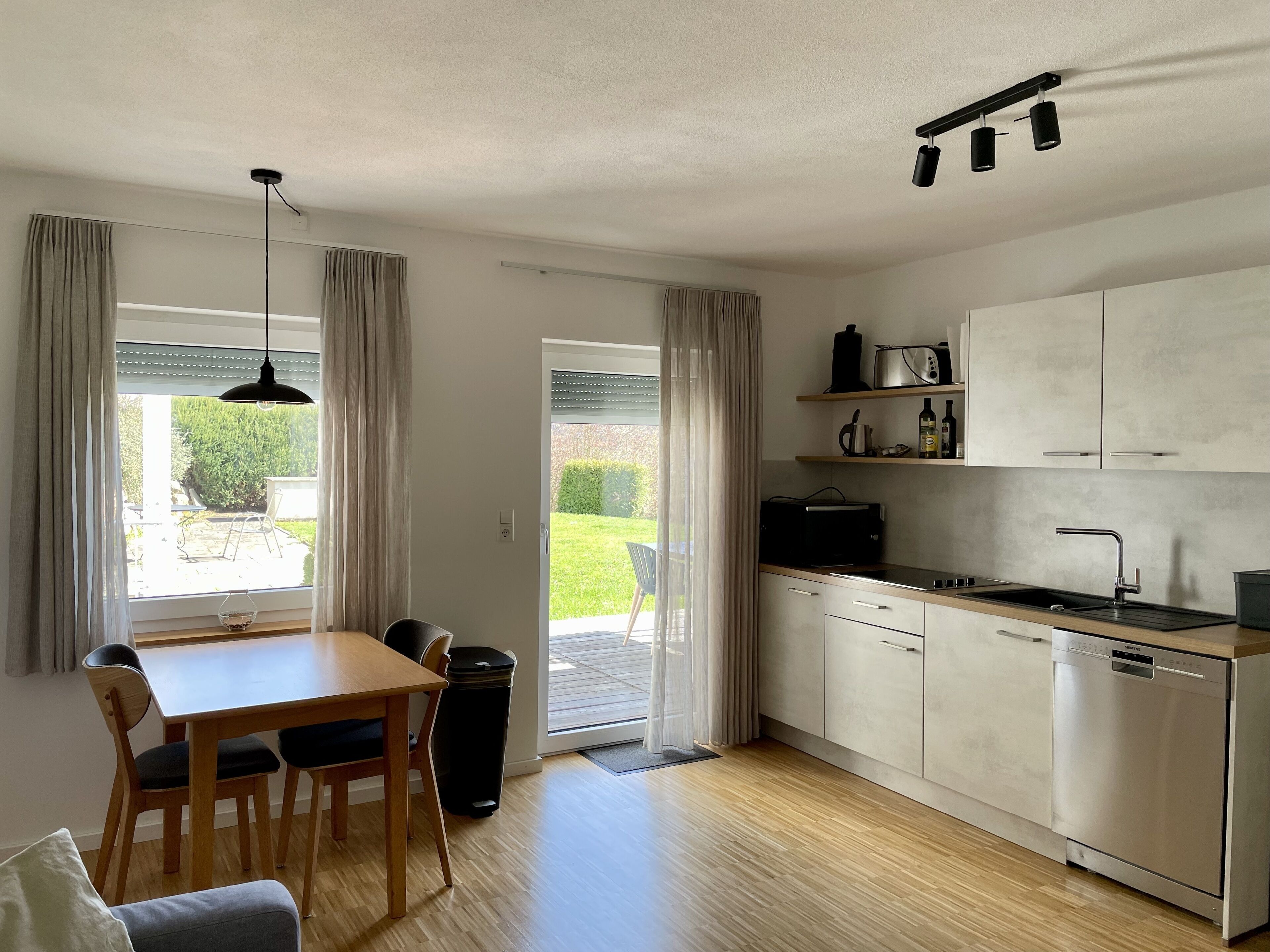 Uma cozinha moderna com área de refeições, piso de madeira e vista para o jardim.