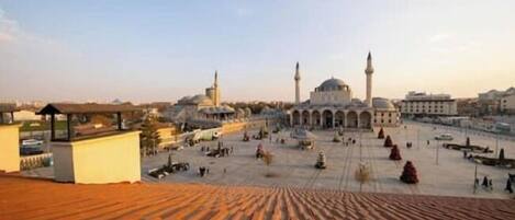 Uma grande praça aberta com uma mesquita e minaretes ao fundo.