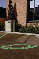 Uma área de estacionamento com um símbolo verde de bicicleta, um edifício de tijolos e uma caixa de utilidades.