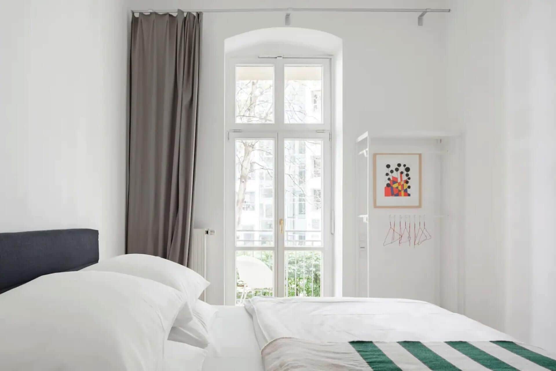 Quarto com cama, uma janela grande e porta que dá para o exterior.
