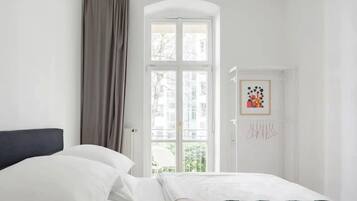 Quarto com cama, uma janela grande e porta que dá para o exterior.