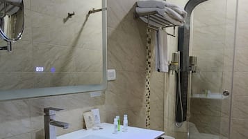 Um banheiro moderno com um espelho grande, pia, vaso sanitário e chuveiro.