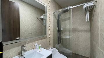 Uma casa de banho moderna com um espelho grande, uma sanita branca, uma casa de wc e uma área de duche com vedação em vidro.