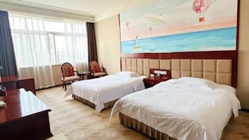 Quarto de hotel com duas camas, uma escrivaninha, uma cadeira e um quadro de uma paisagem marítima.