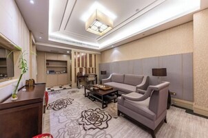 Uma sala de estar moderna com um sofá, poltronas, uma mesa de centro e uma televisão.