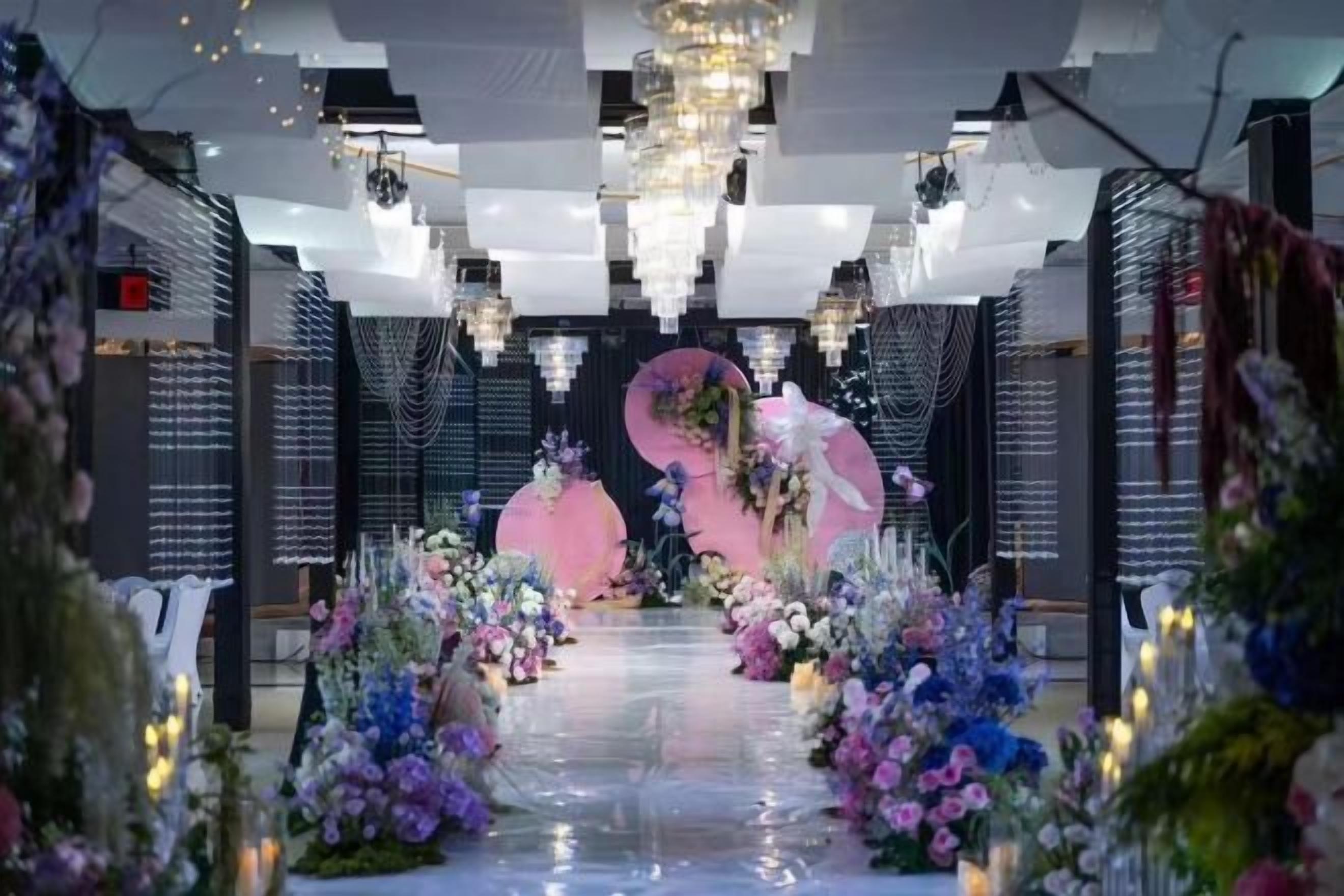 Espaço interno com palco central, arranjos florais e luminárias modernas.