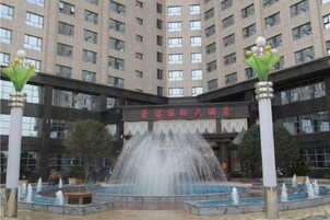 Hotel com uma fonte central, vários andares e uma placa com caracteres chineses.