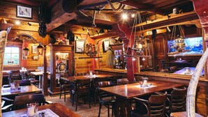 Um interior rústico com mesas e cadeiras de madeira, um espaço de bar e decoração náutica.