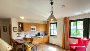 Um espaço de estar compacto com cozinha compacta, área de jantar e um espaço de estar com uma cadeira vermelha.
