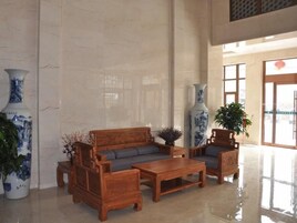 Um hall de entrada com um conjunto de sofá de madeira, dois vasos grandes e uma planta em vaso.